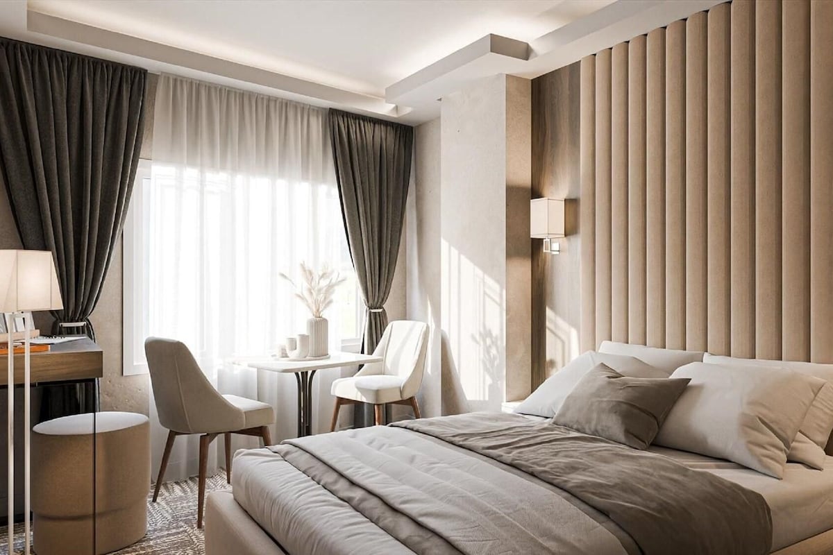 Quarto de hotel moderno com cama, escrivaninha, cadeira e uma pequena mesa.
