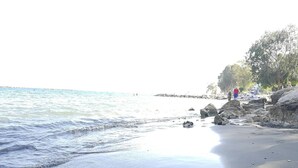 Uma praia com águas calmas, areia dourada e algumas rochas.
