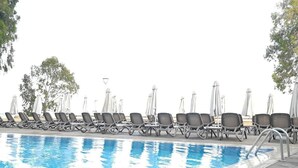 Piscina com espreguiçadeiras e guarda-sóis.