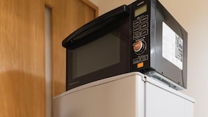 Um frigorífico compacto com um micro-ondas embutido no topo, um painel de comandos e o logótipo Sharp.