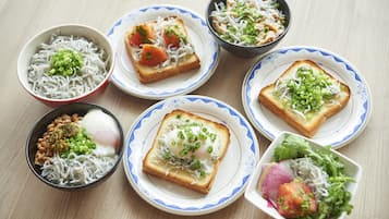 Uma mesa com diversos pratos, incluindo macarrão, tigelas de arroz e pratos com legumes e ovos.