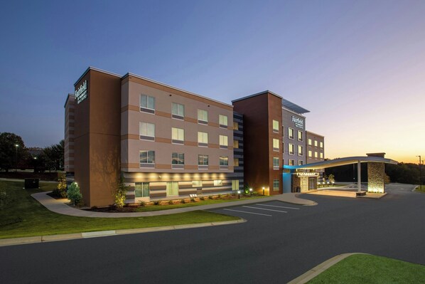 Um hotel com design moderno, destacando uma entrada imponente e uma área de estacionamento.