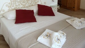 Cama bem arrumada com almofadas vermelhas, uma peça de arte decorativa acima e um guarda-roupa de madeira ao fundo.