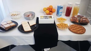 Uma mesa com diversos alimentos, incluindo sanduíches, bolachas e frutas.