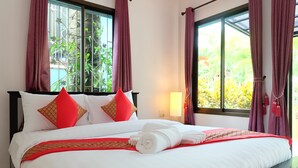 Cama bem arrumada com lençóis brancos, almofadas vermelhas e um edredom com padrão vermelho e branco.