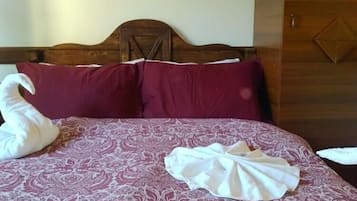 Cama com colcha estampada, duas almofadas e duas toalhas dispostas sobre a cama.