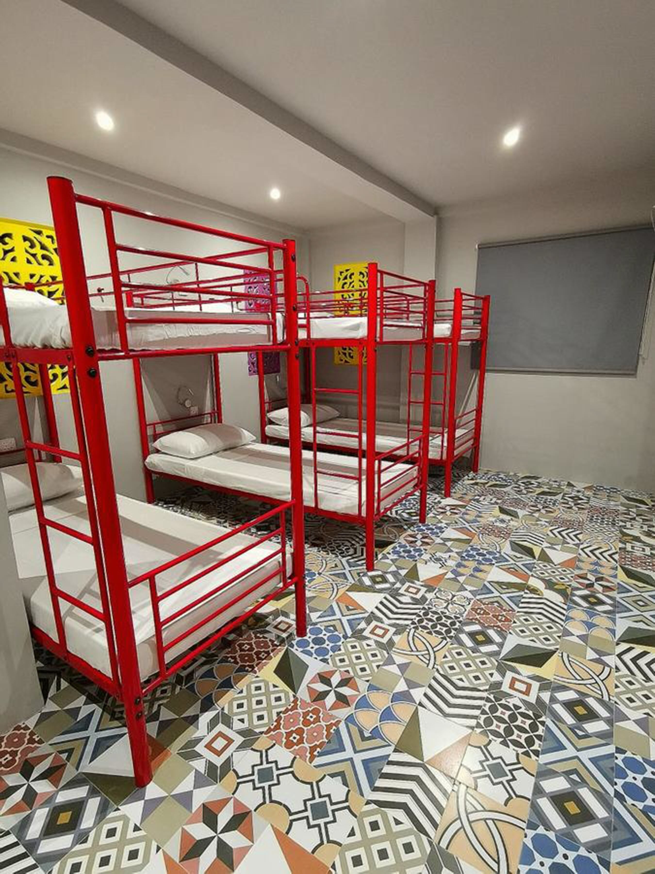 Um quarto de dormitório com beliches, pisos de azulejos estampados e um quadro branco na parede.