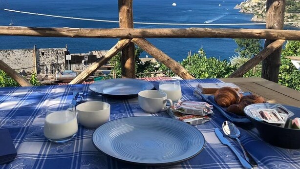 Mesa posta para o café da manhã, vista para o mar e uma cidade costeira.