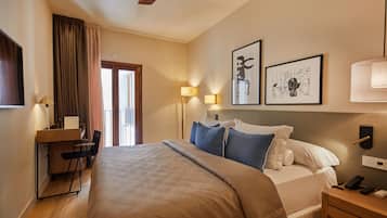 Quarto de hotel com cama, escrivaninha, cadeira, abajur, obras de arte e ventilador de teto.
