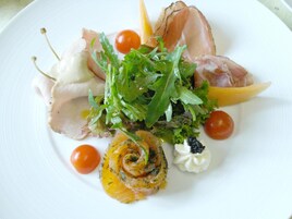 Um prato com diversos alimentos, incluindo vegetais verdes, tomates e uma fatia de carne.