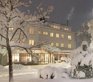 Um hotel com vários andares, grandes janelas e paisagem coberta de neve.