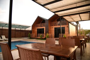 Uma casa de madeira moderna com piscina, área de estar ao ar livre e varanda coberta.