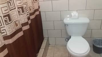 Um banheiro com vaso sanitário, lixeira e cortina de chuveiro estampada.