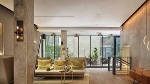 Sala moderna com sofá, mesa de centro e vista para o exterior através de grandes janelas.