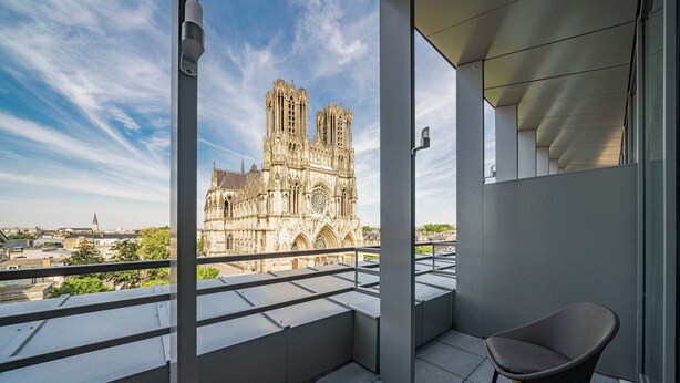Uma varanda com duas cadeiras, vista de uma catedral e céu claro.