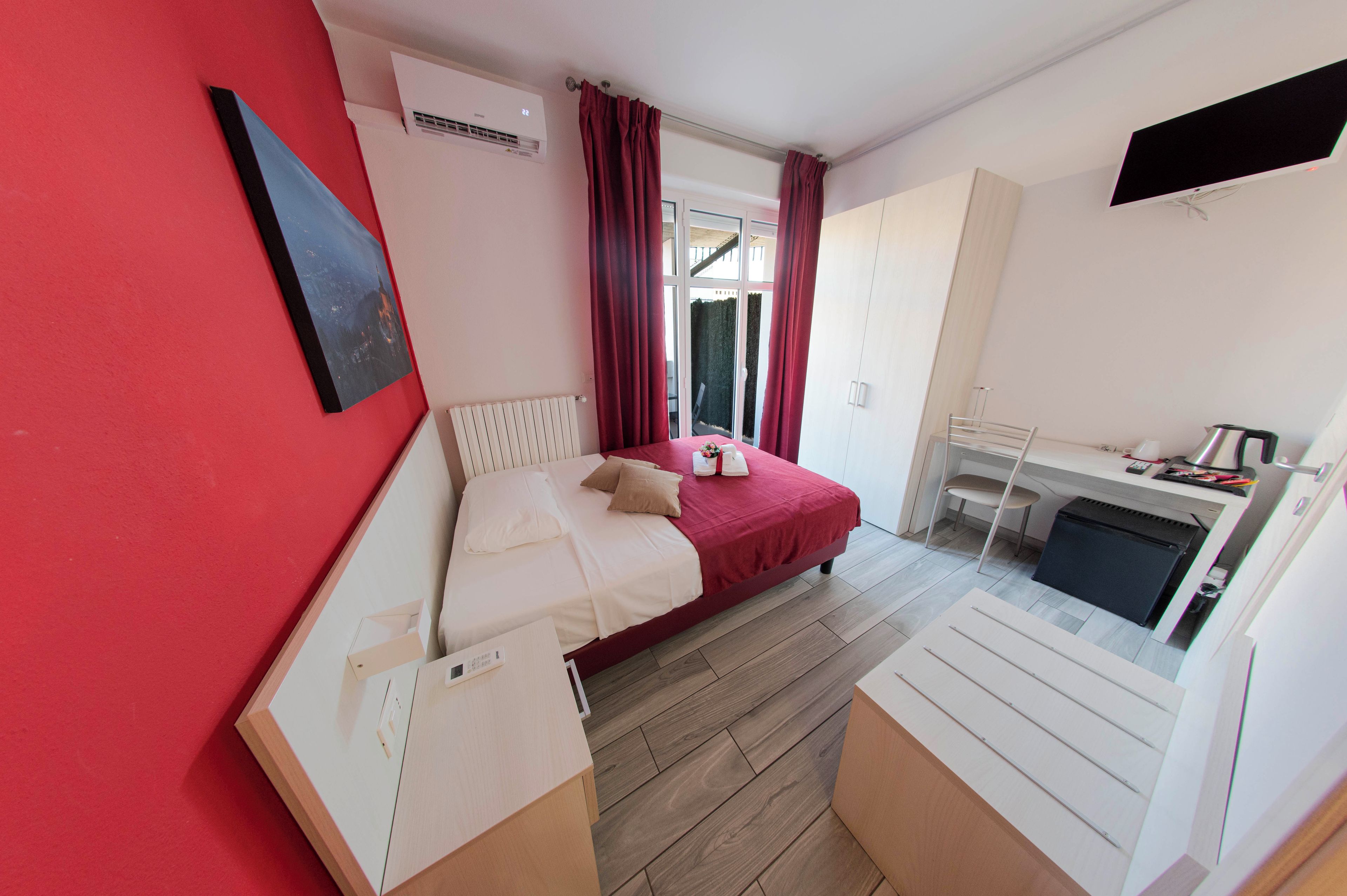 Quarto compacto com cama, escrivaninha e cozinha compacta.