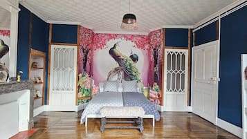 Quarto com cama, um mural decorativo e ventoinha no teto.