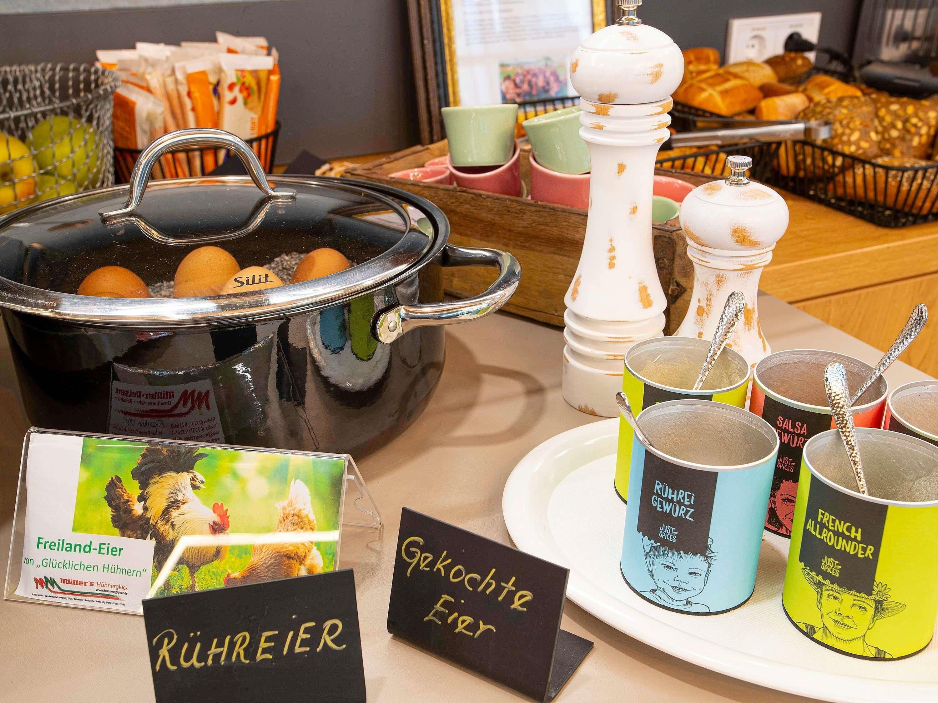 Disposição para o café da manhã com uma panela de ovos, saleiro e pimenteiro, e recipientes de temperos etiquetados.