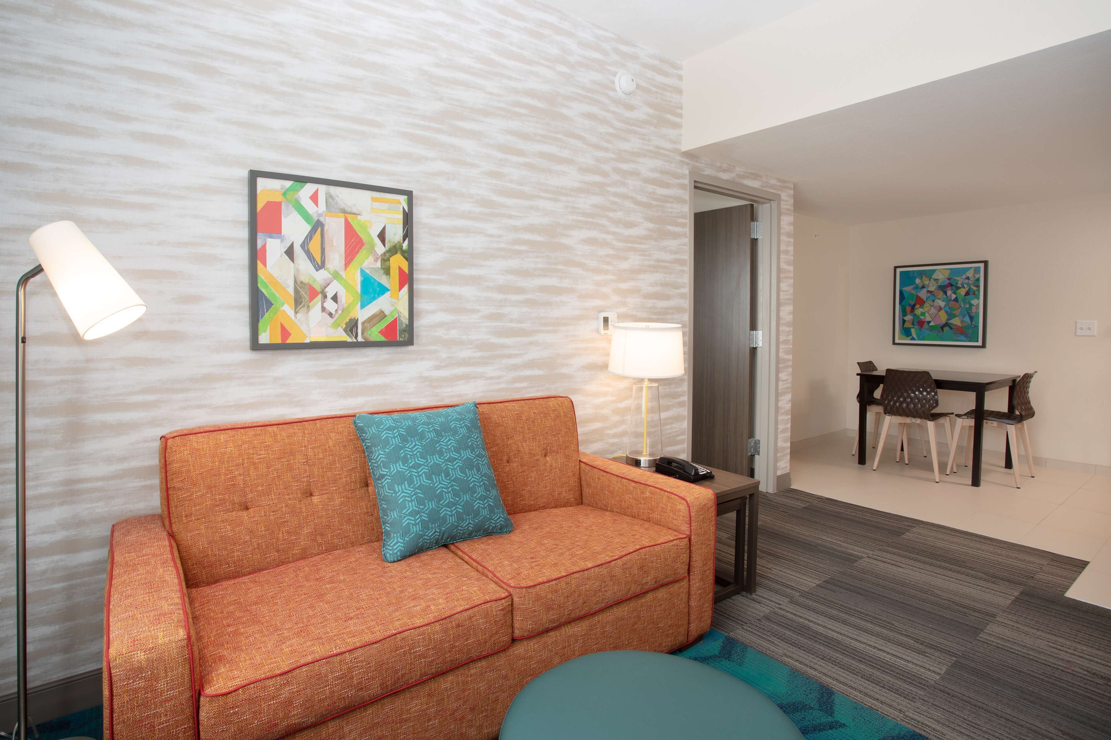 Uma sala de estar moderna com sofá, duas luminárias e um espaço de jantar com mesa e cadeiras.