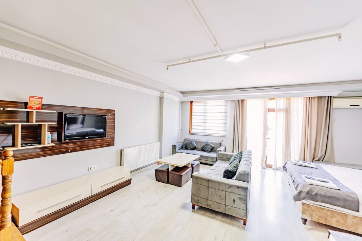 Uma sala de estar moderna com televisão de tela plana, sofá e cama.