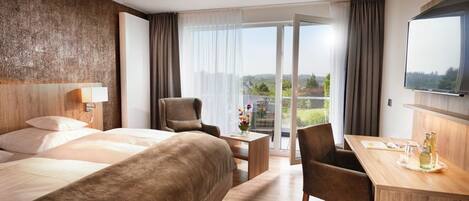 Quarto de hotel moderno com duas camas, uma escrivaninha, uma cadeira e uma janela grande com vista para o exterior.