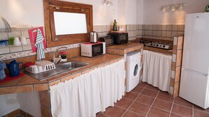 Uma cozinha compacta com pia, micro-ondas, torradeira e máquina de lavar.