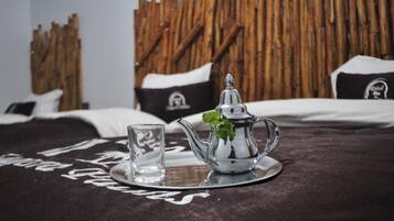Quarto bem arrumado com uma cama, uma mesa de cabeceira com uma chaleira e um copo, e um painel decorativo na parede.