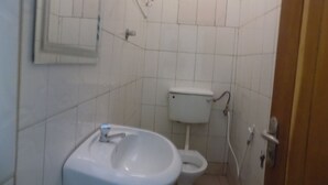 Um banheiro pequeno com azulejos brancos, pia branca e vaso sanitário.