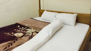 Cama bem arrumada com lençóis brancos e manta com padrão floral.