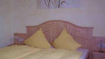 Uma cama com cabeceira de madeira, dois travesseiros amarelos e um cobertor amarelo.