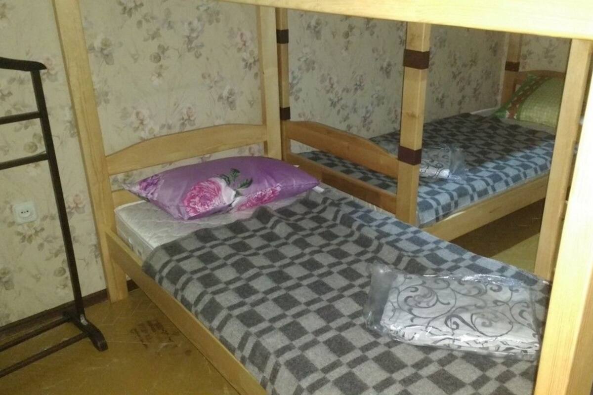 Uma cama beliche com colcha xadrez e travesseiro roxo.