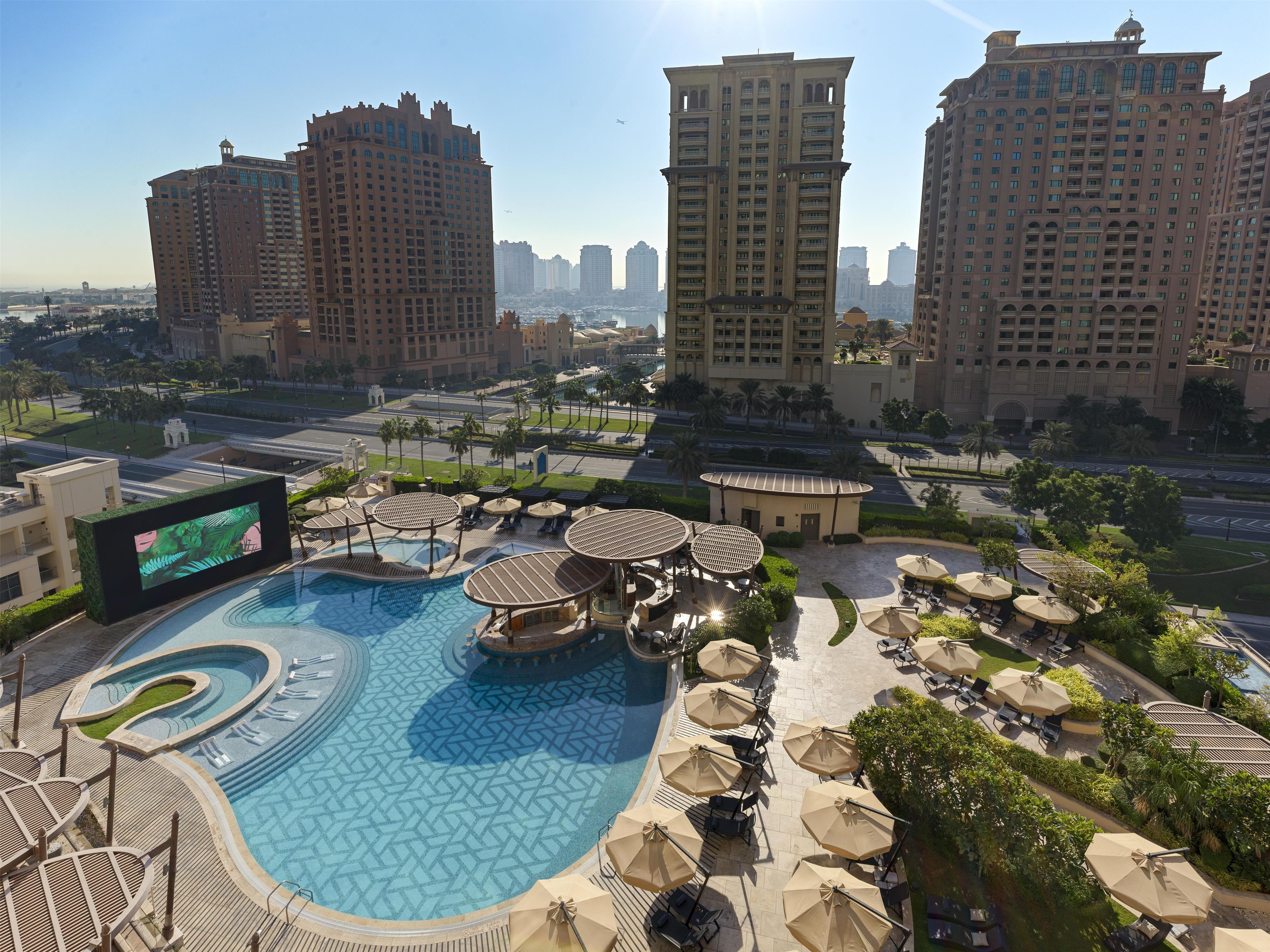 Um resort com piscina, espreguiçadeiras e uma tela grande.