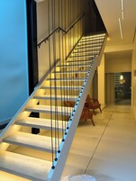 Uma escadaria moderna com design minimalista, apresentando corrimão branco e balaústres pretos.