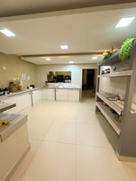 Uma cozinha moderna com armários brancos, uma ilha central e uma prateleira embutida com utensílios de cozinha.