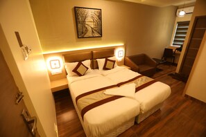 Quarto de hotel com uma cama grande, mesas de cabeceira, escrivaninha e uma cadeira.