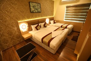 Quarto de hotel com uma cama grande, duas mesas de cabeceira, uma escrivaninha pequena e um objeto decorativo na parede.