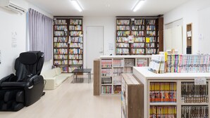 Uma biblioteca com estantes, uma poltrona de massagem e um balcão de recepção.