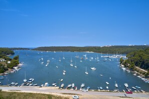 Uma marina com vários barcos atracados, rodeada por vegetação e colinas ao fundo.