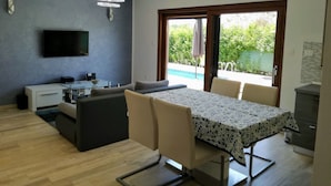 Uma sala de estar moderna com mesa de jantar, sofá e televisão.