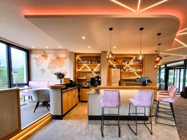 Uma área de bar moderna com um mapa-múndi na parede, banquetas e diversas garrafas.