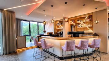 Cozinha moderna com área de bar, banquetas, iluminação pendente e vista para o exterior.