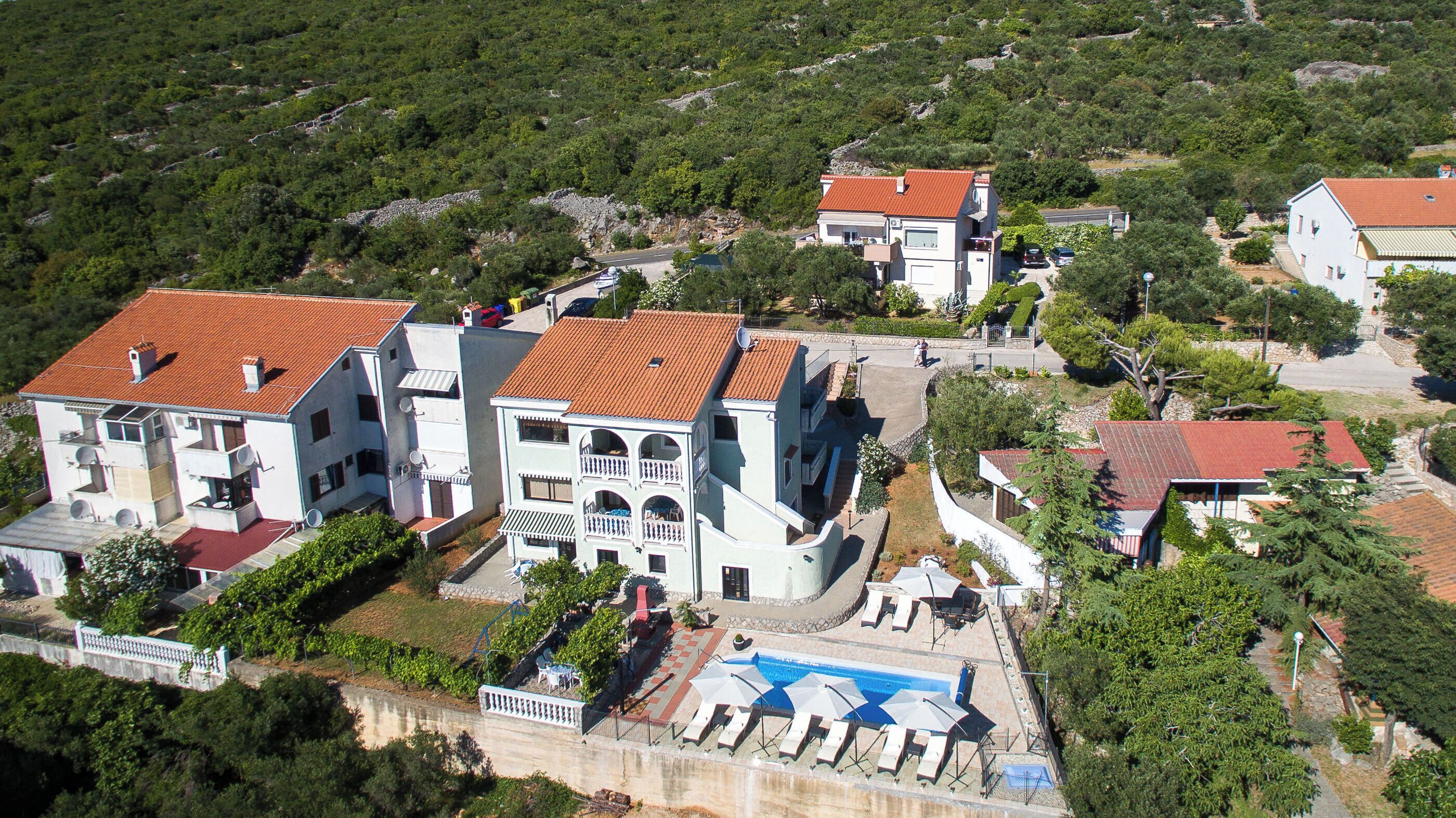 Um bairro residencial com várias casas de dois andares, uma piscina e um muro de pedra.