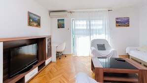 Quarto de hotel moderno com televisão de tela plana, escrivaninha, cadeira confortável, cama e obras de arte nas paredes.
