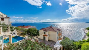 Um imóvel costeiro com piscina, vista para o mar e céu claro.