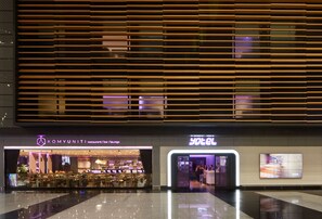 Interior moderno com restaurante, bar e área de lounge, uma recepção e entrada do hotel.