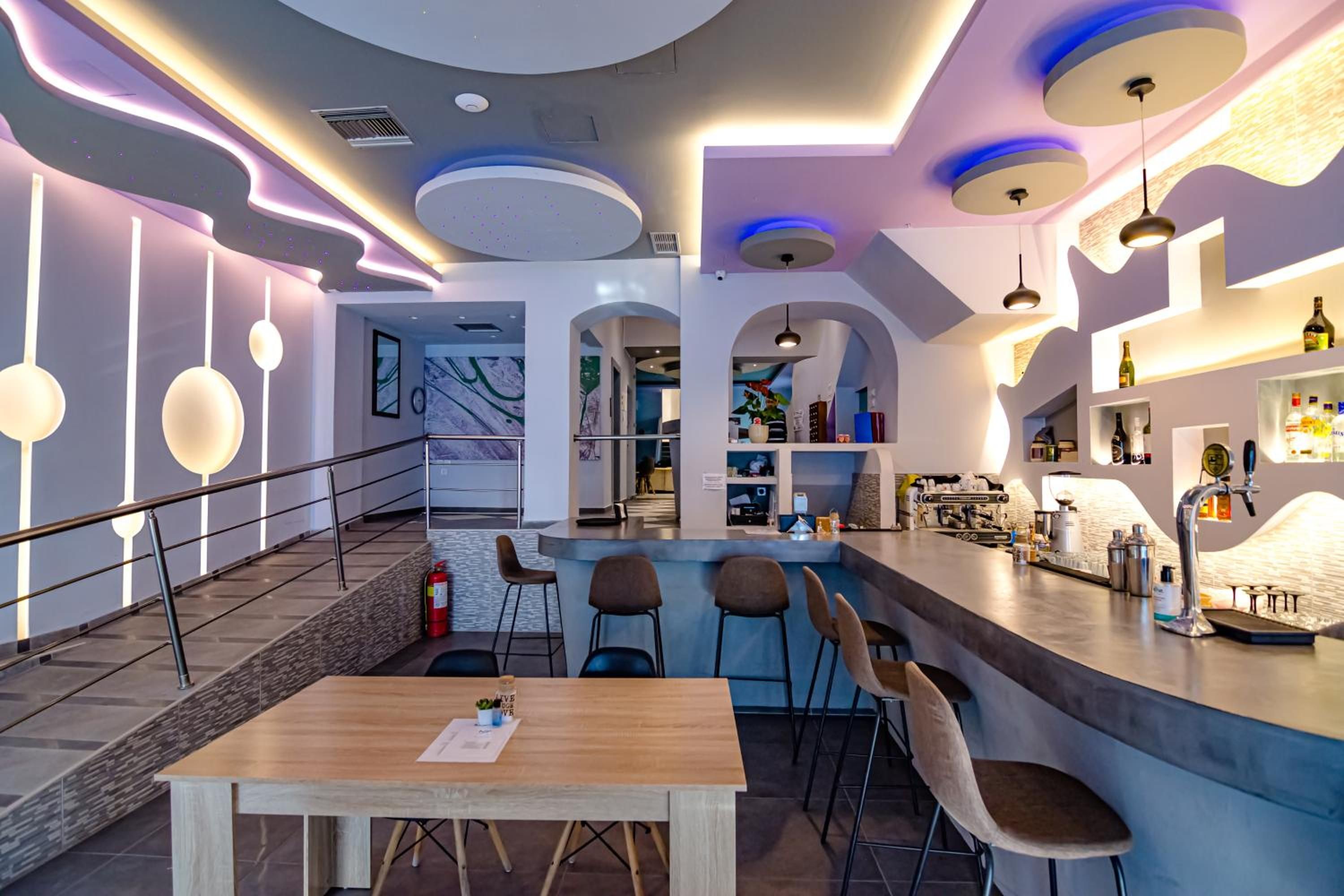 Uma área de bar moderna com balcão, banquetes e um espaço de estar com mesa.