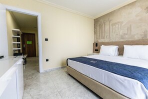 Quarto de hotel com cama, escrivaninha e guarda-roupa.