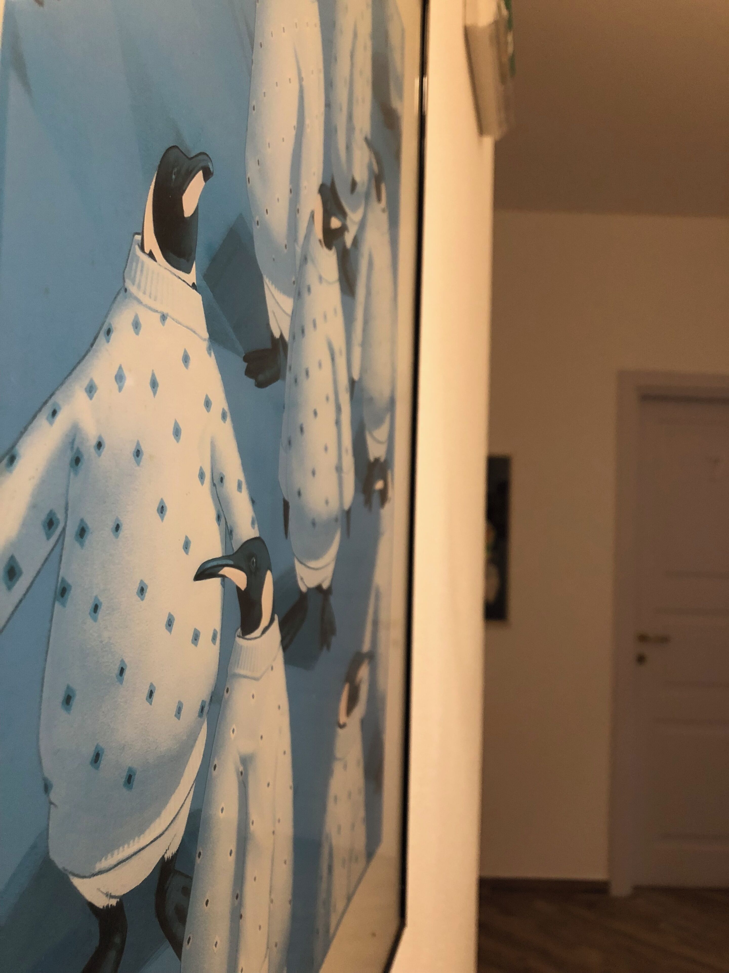 Uma parede com figuras de pinguins vestindo suéteres.
