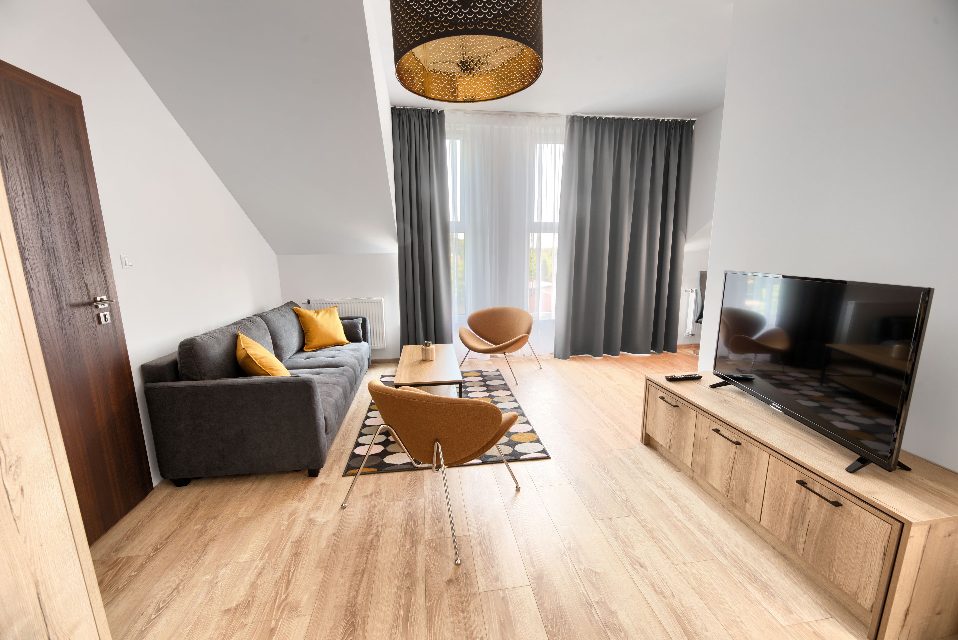 Uma sala de estar moderna com um sofá, poltronas, uma TV e um aparador de madeira.