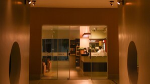 Um lobby de hotel moderno com divisória de vidro, balcão de recepção e tapete estampado no chão.